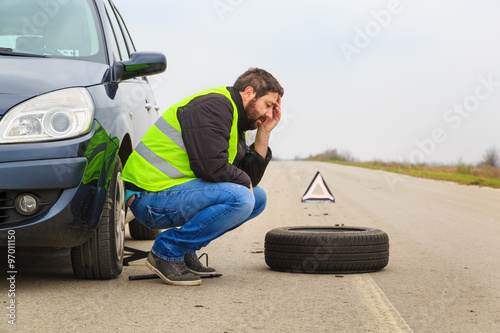 "Frustrated man having trouble wiht changing a flat tire" Stock photo ...