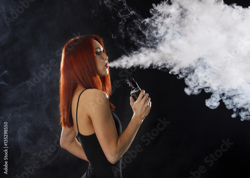 "Young beautiful woman vaping e-cigarette." photo libre de droits sur ...