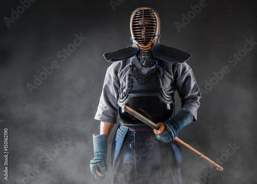 "Kendo master standing in traditional armor .He holds bamboo sword ...