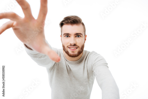"Handsome guy reaching out to the camera isolated. Young man trying to ...