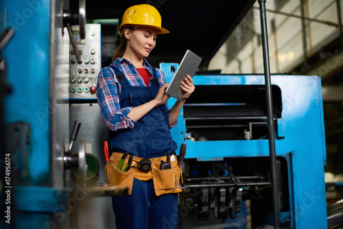 "Portrait of female machine operator using digital tablet while working ...