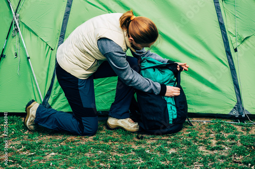 "female unpack a backpack near tent, after a long day of hiking and ...