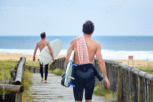 Two Surfers Running With Surfboards On The Beach Men Walking Along