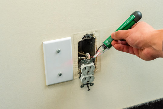 Professional Electrician Testing Wall Outlet for Safety Assurance