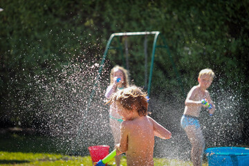 Happy family doing water gun battle in swimming pool on a sunny day ...
