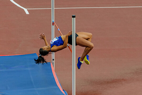 Female Athlete Clearing High Jump Bar Grass Field