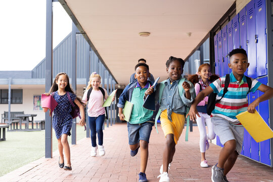 Diverse Group of Happy Students Running Excitedly in School Corridor